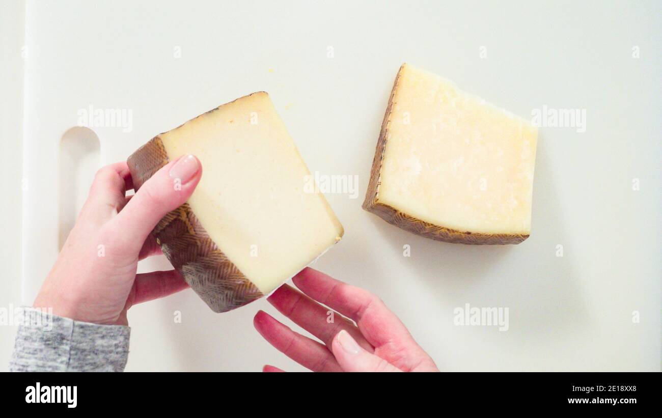 Flat lay. Slicing a large slice of gourmet cheese on a white background ...