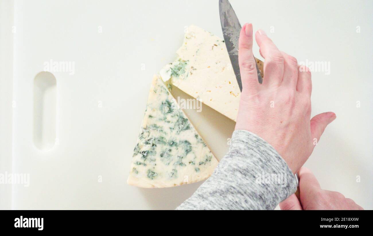 Flat lay. Slicing a large slice of gourmet cheese on a white background ...