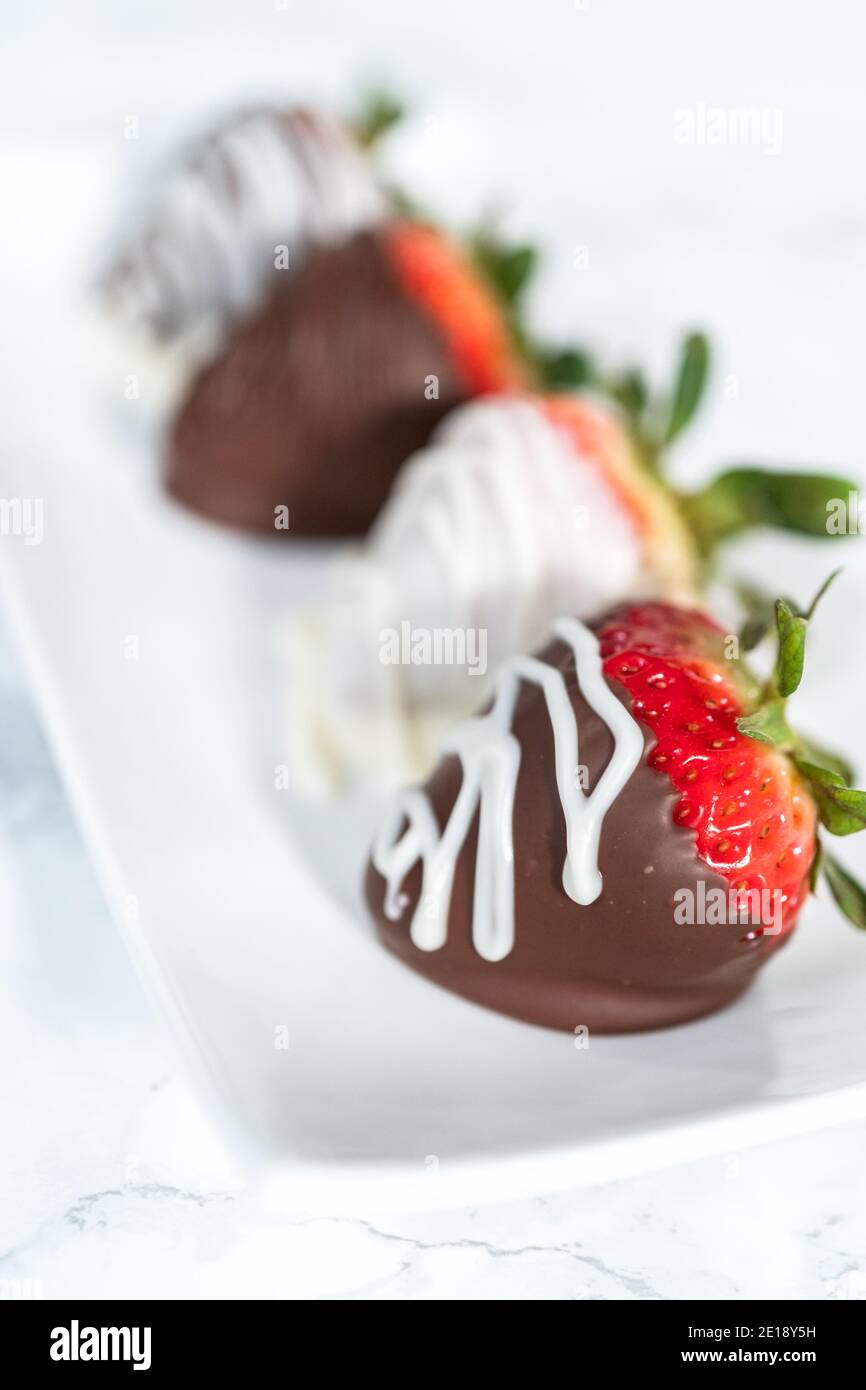 White and dark chocolate dipped strawberries on a white serving plate ...