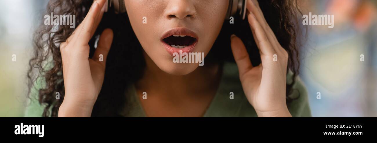 partial view of shocked african american woman listening podcast in ...