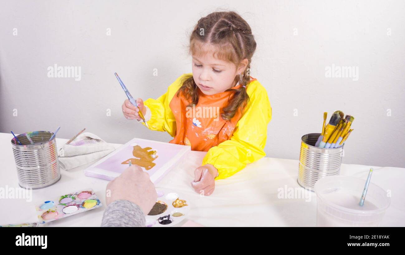 Little girl painting with acrylic paint on canvas with her mother for a ...