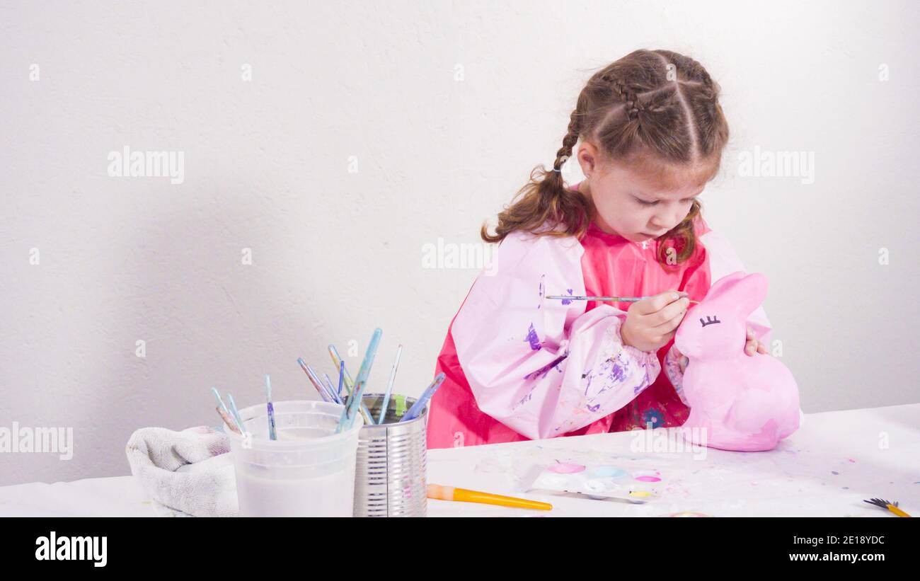 Little girl painting paper mache figurines with acrylic paint for her ...