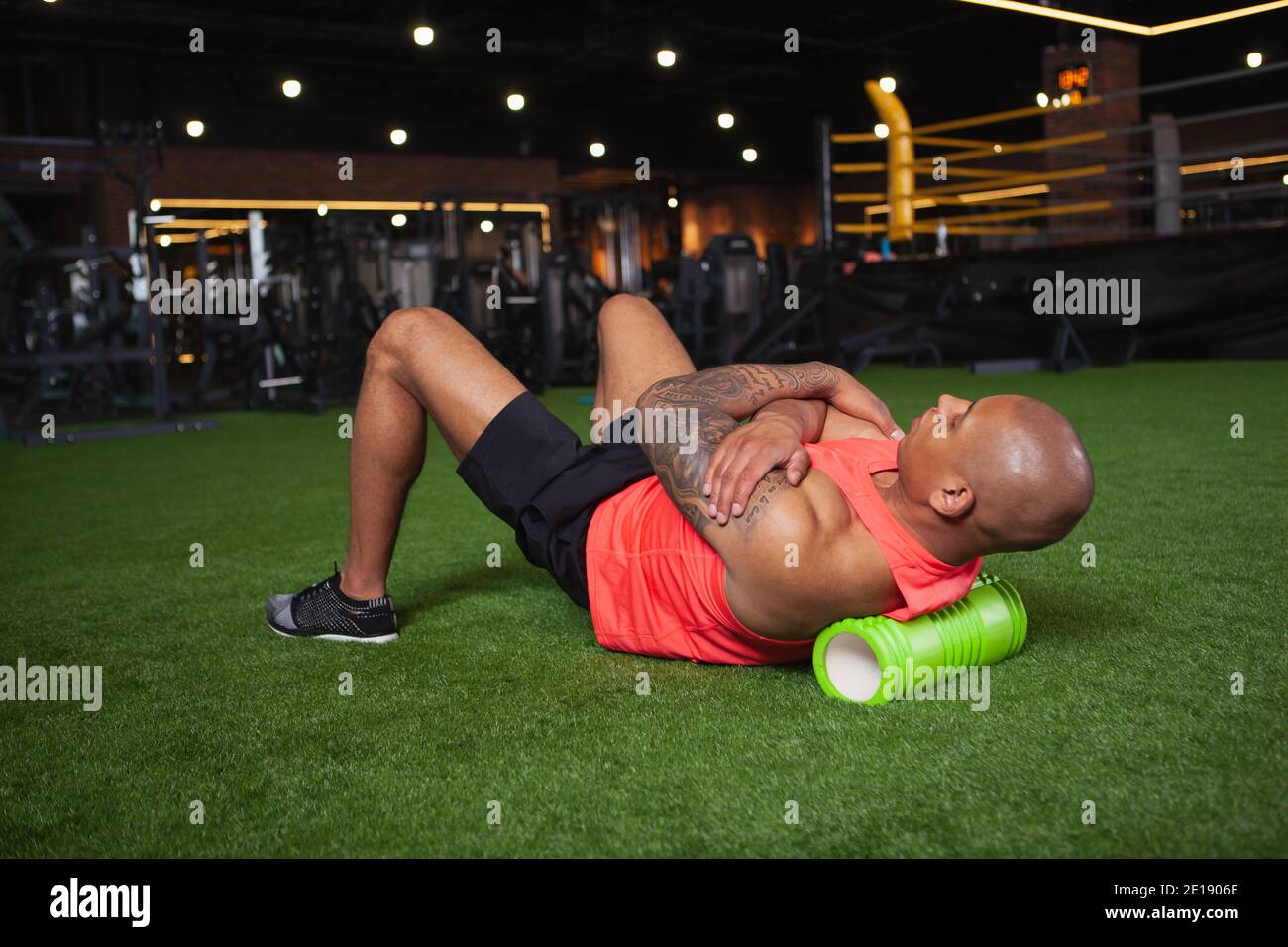 Muscular male athlete using foam roller after woring out at the gym ...