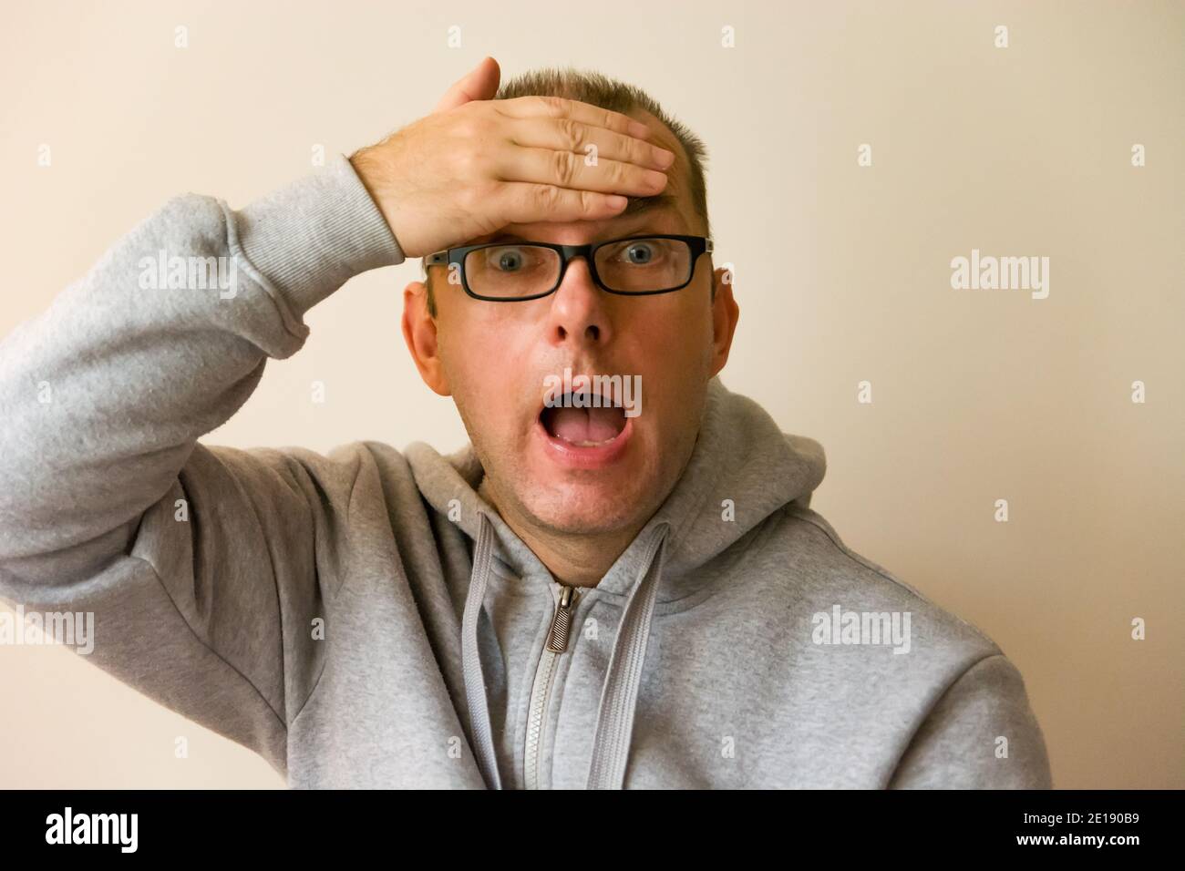 Surprised man holding on to his forehead Stock Photo - Alamy