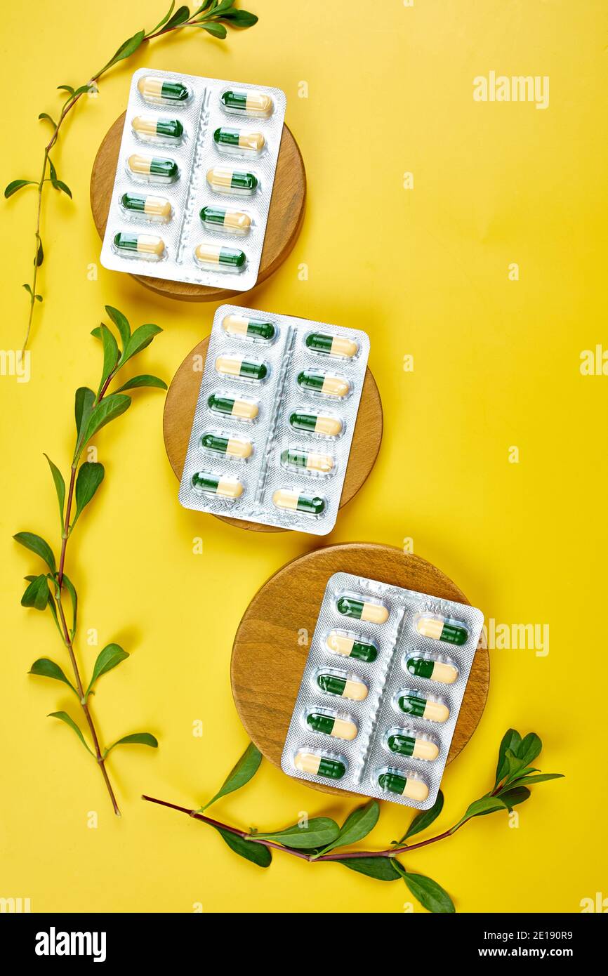 Flat lay Organic medical pills, capsules in blisters with green leaf ...