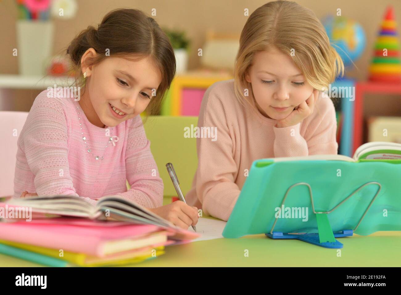 Portrait of two beautiful little girls doping homework Stock Photo - Alamy