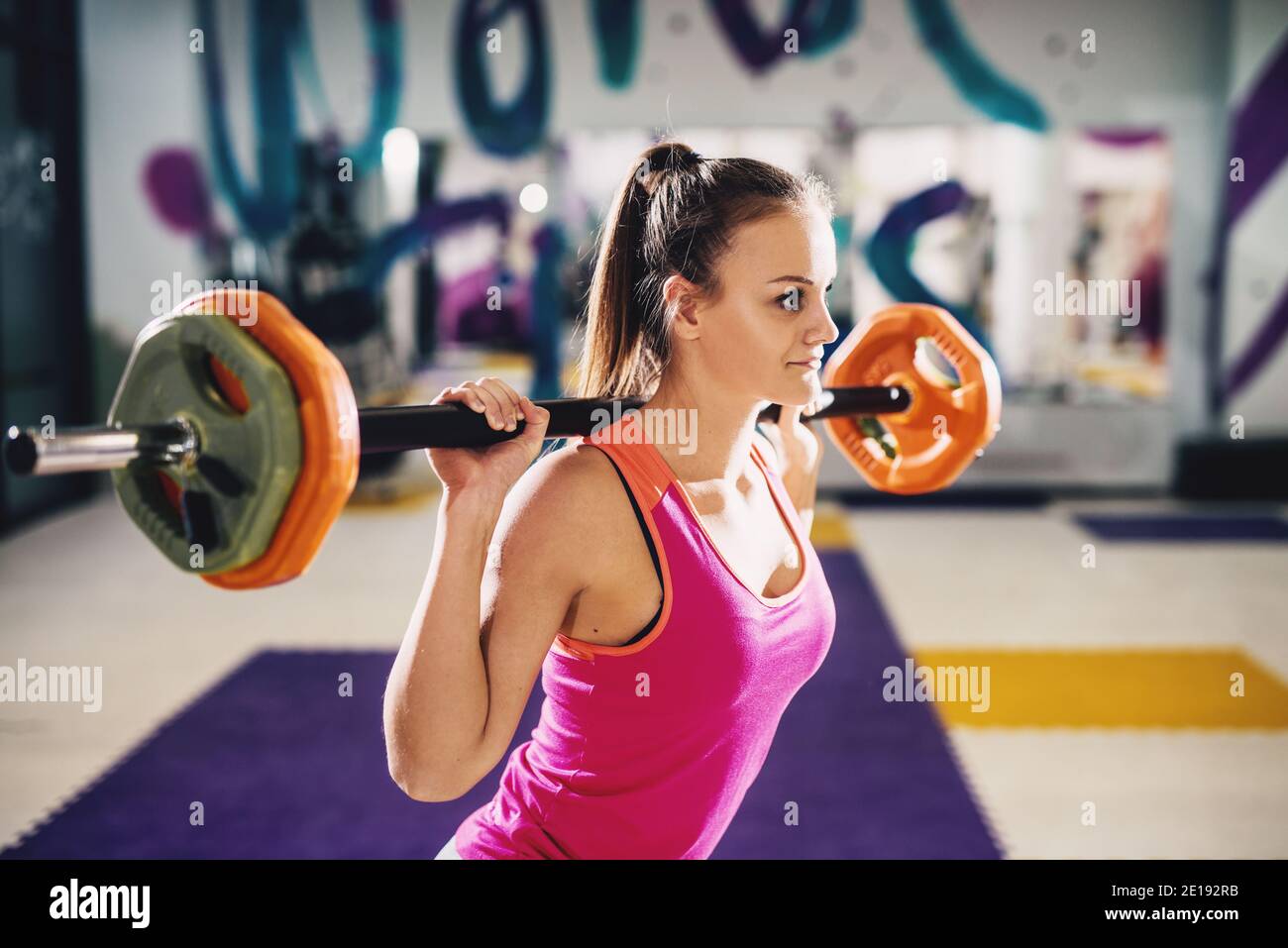 Beautiful young fitness shape girl doing squats with a barbell in the ...