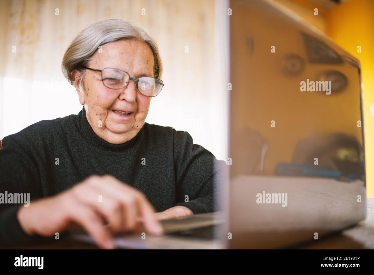 Happy cheerful elderly woman typing on the laptop keyboard Stock Photo ...