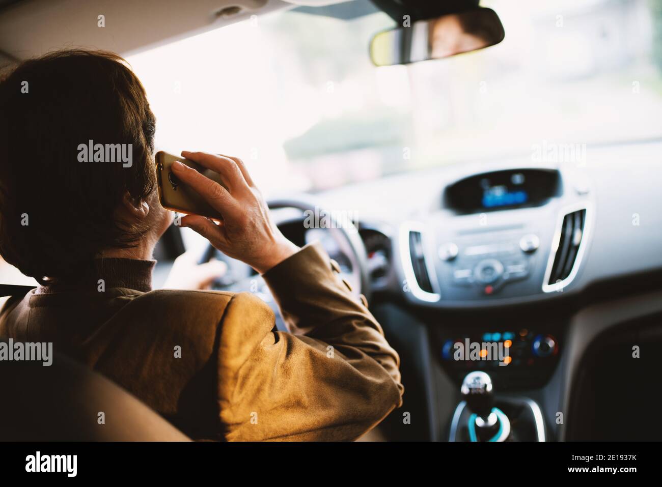 Rear car view of senior woman talking on the phone while driving ...