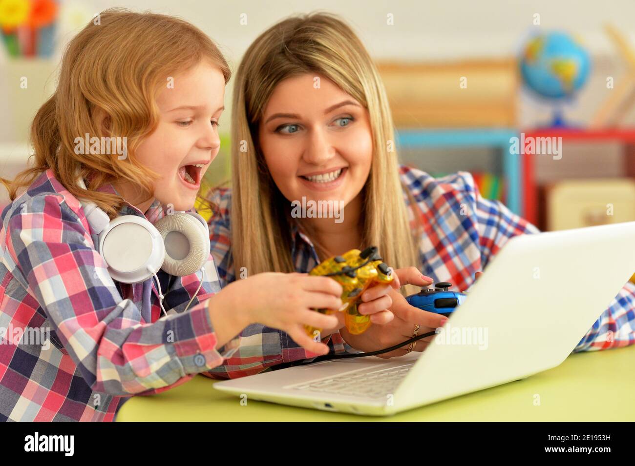 Mother and daughter using laptop together playing game Stock Photo - Alamy