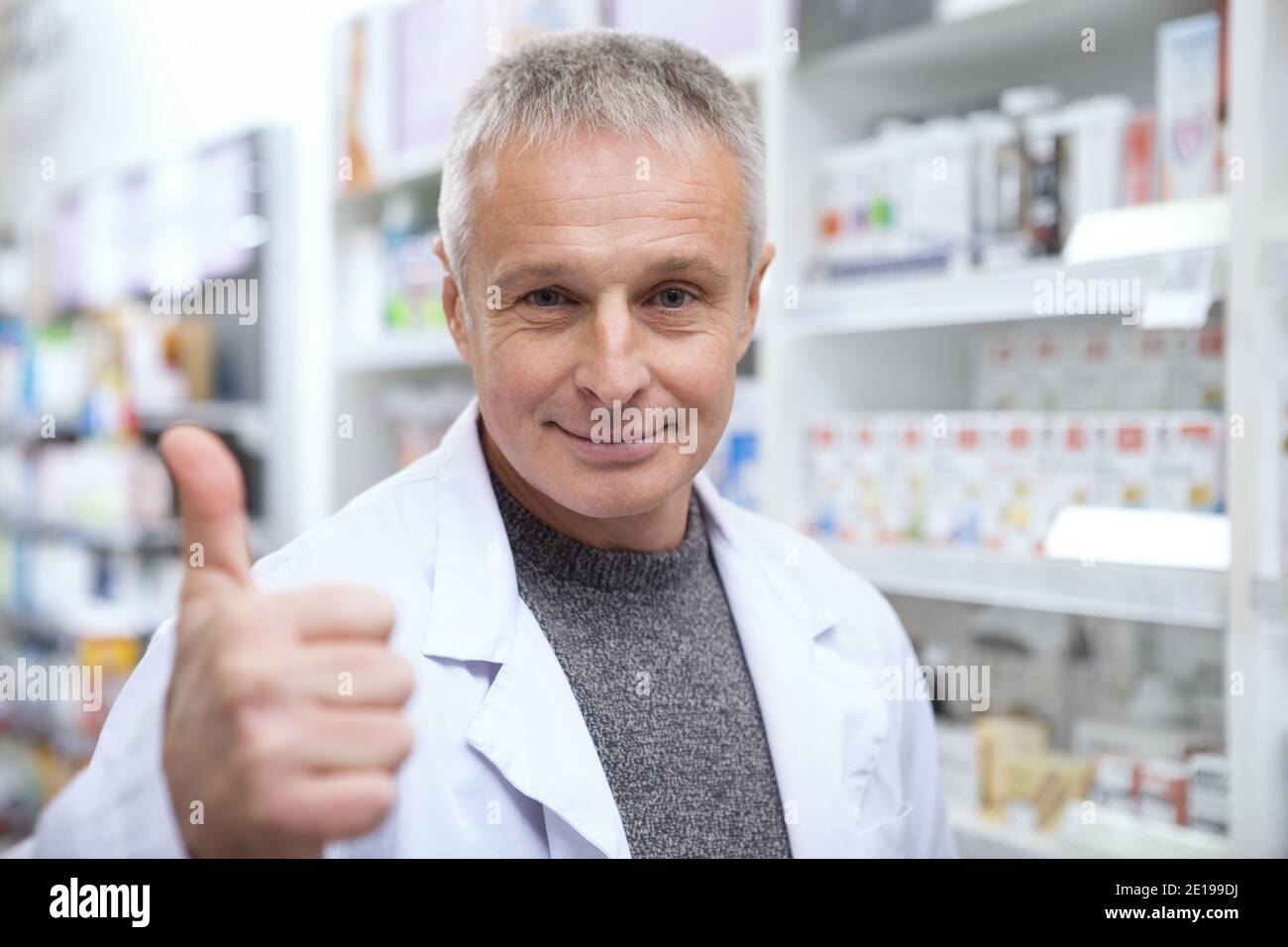 Cheerful senior pharmacist smiling joyfully, showing thumbs up, copy ...