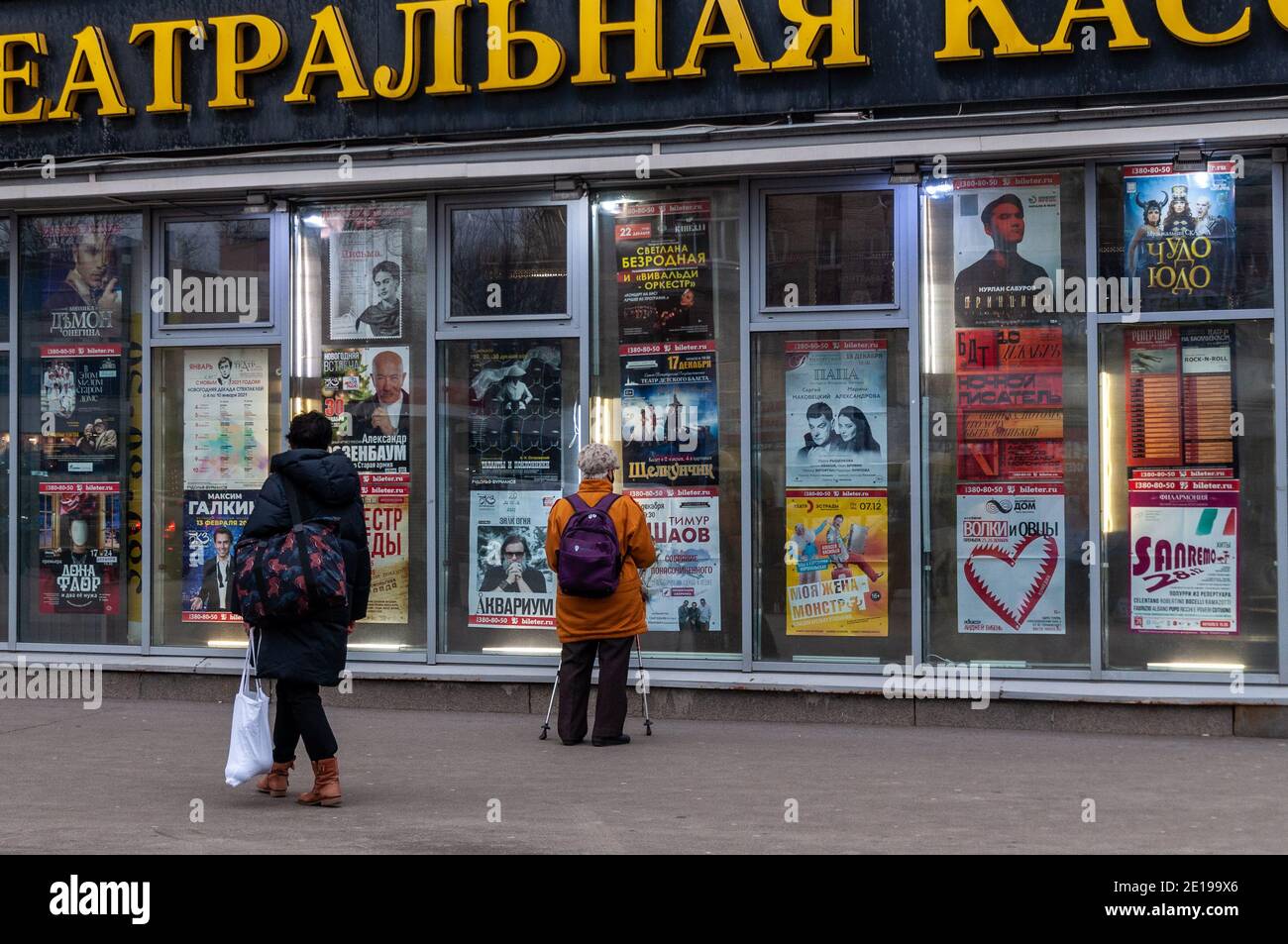 two women in front of the posters of performances at the theater box ...