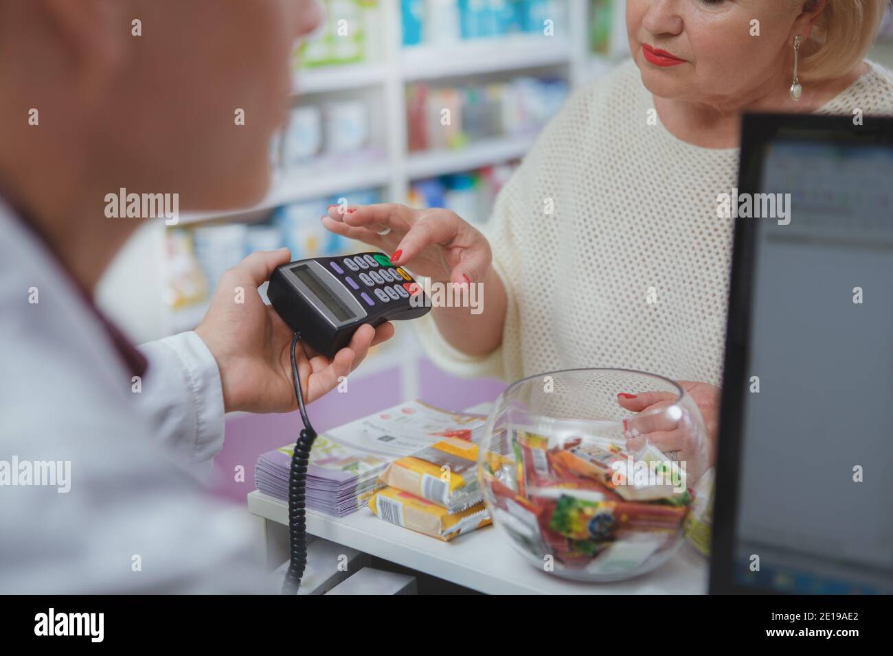 Cropped shot of a senior woman paying by credit card at the pharmacy ...