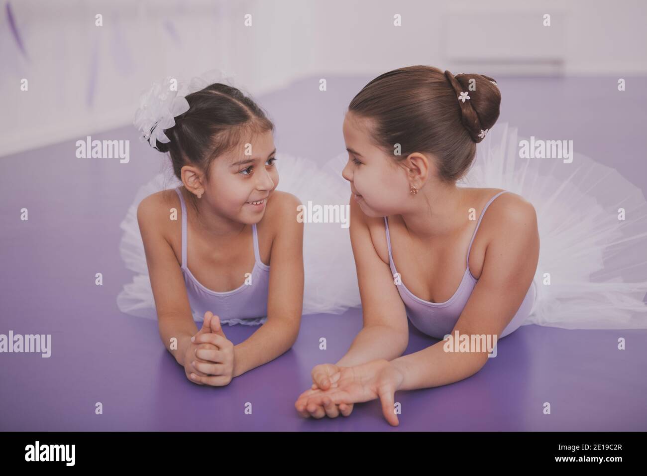 Happy little girls relaxing after ballet class, talking, lying on the ...