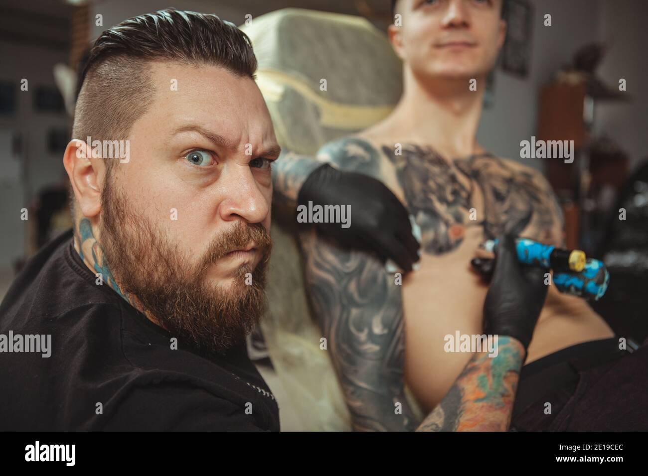 Bearded professional tattoo artist making angry face to the camera ...