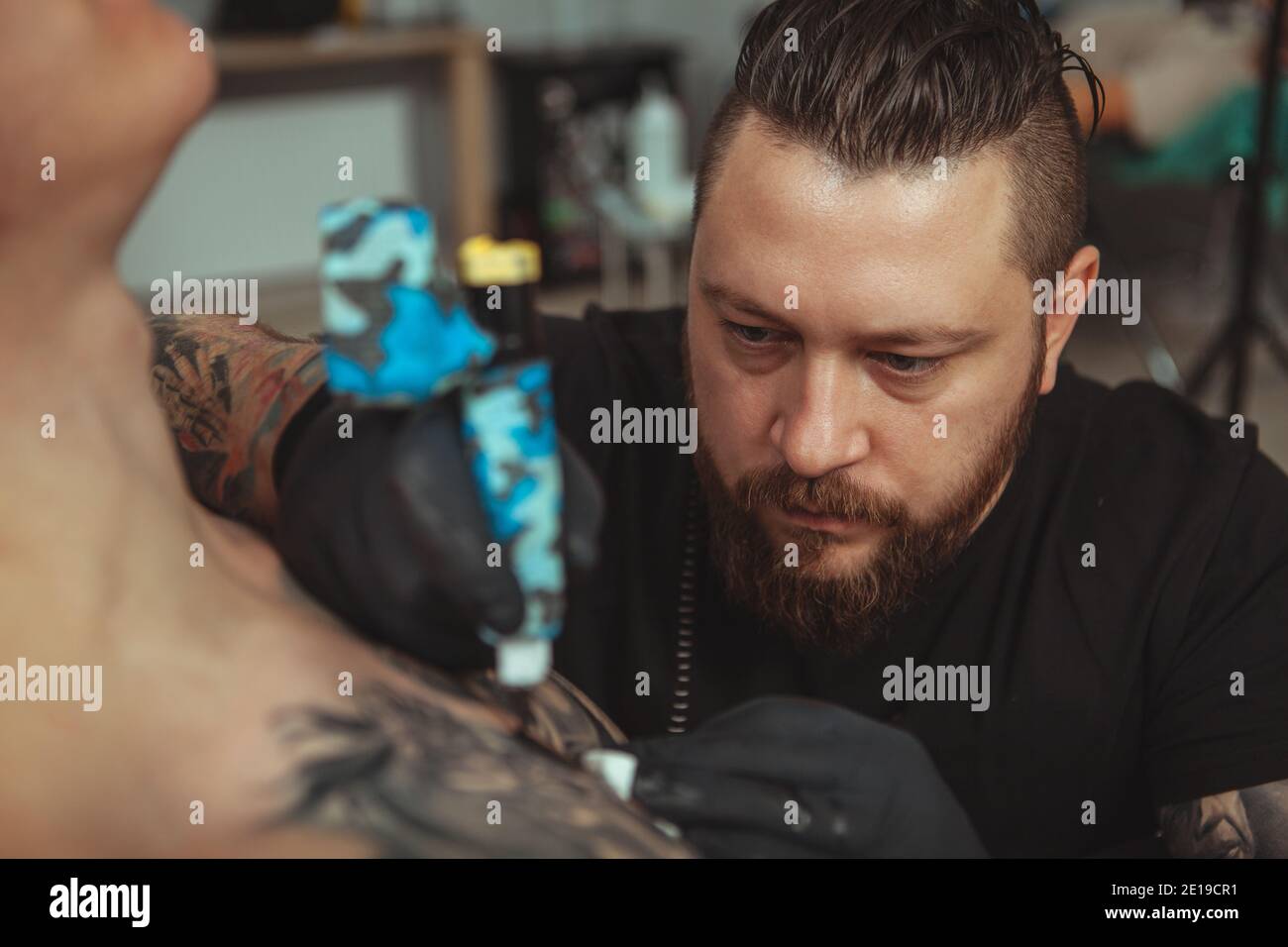 Professional tattoo artist looking focused, working at his studio ...
