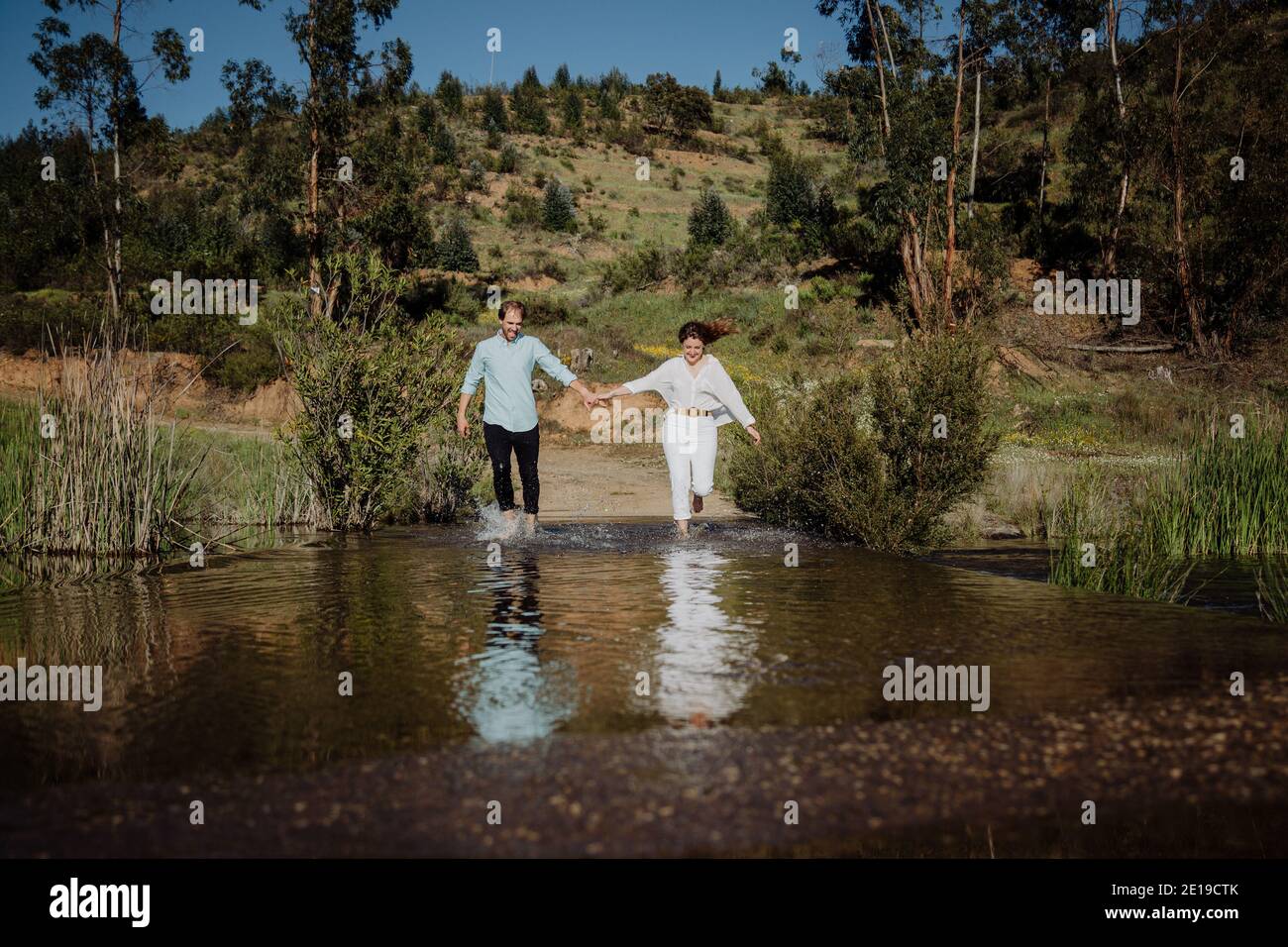 Couple running through the water, splashing each other. Welcoming the ...