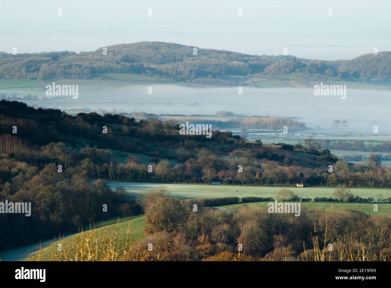 Layers of mist in a valley in the countryside with hills, green fields ...