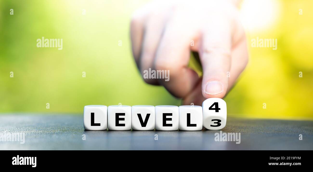 Hand turns dice and changes the expression "level 3" to "level 4 Stock Photo - Alamy