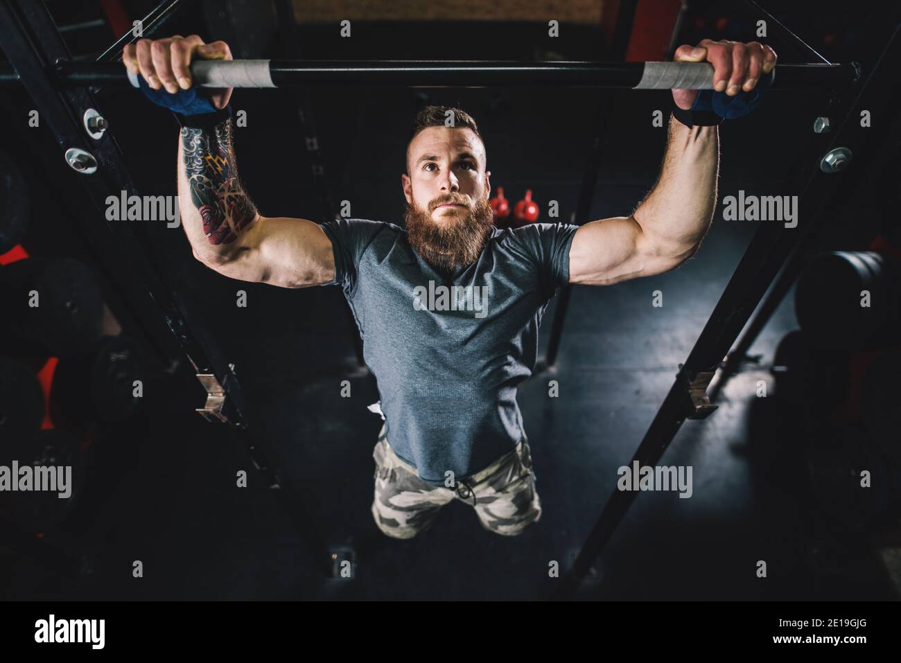 Portrait view of strong active muscular bodybuilder guy doing pull-ups ...