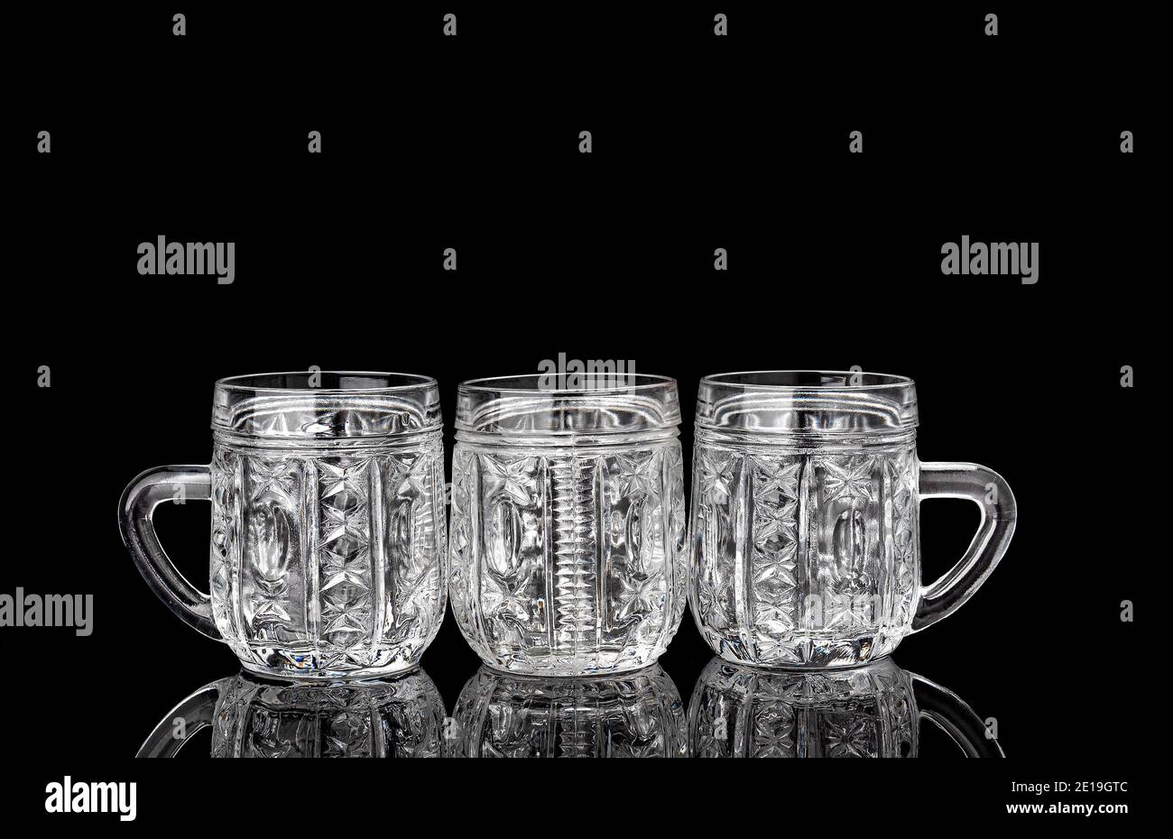 Three empty crystal cups on a black background with reflection. Crystal ...