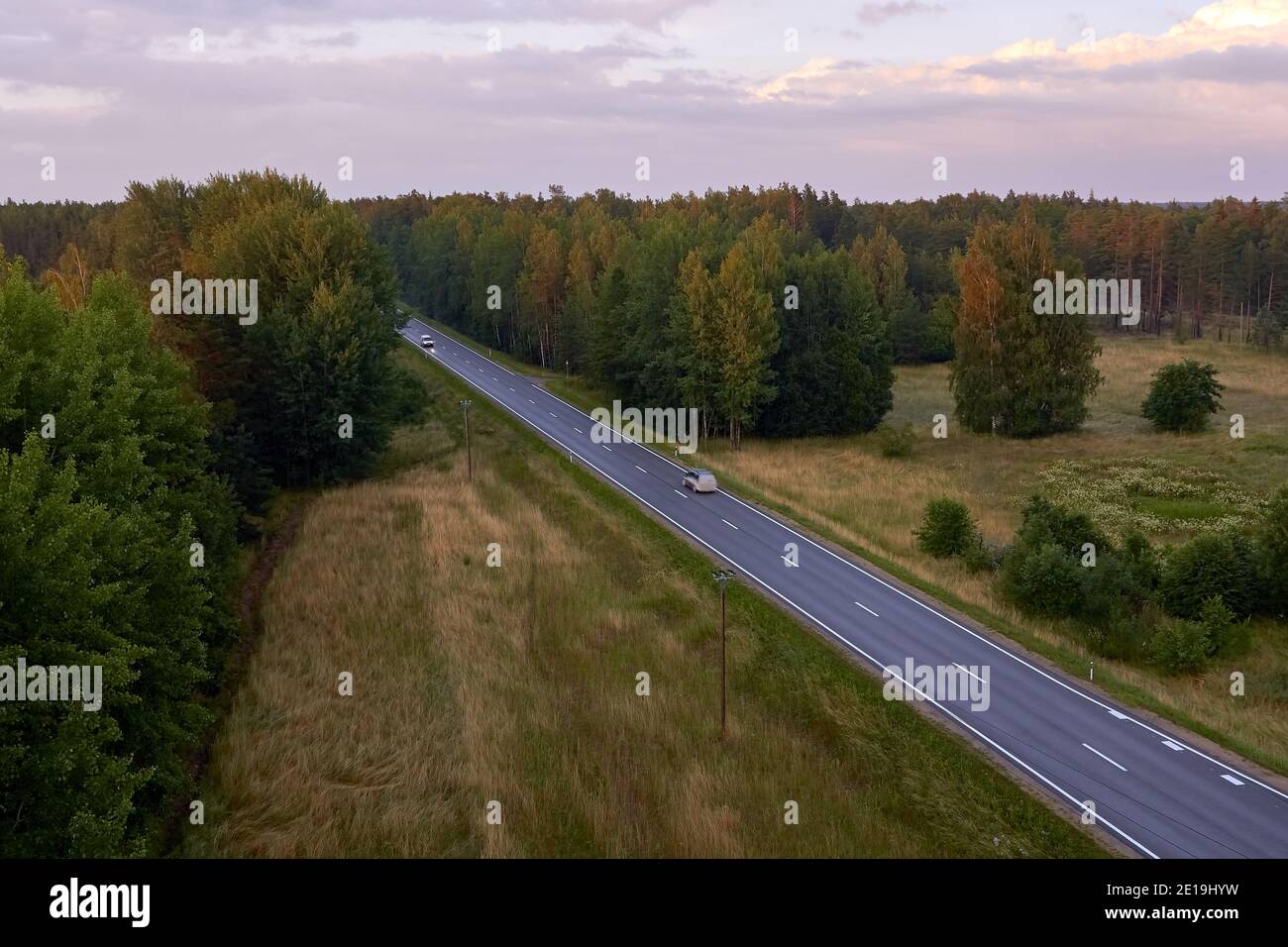Driving cars on a rural asphalt road next to forest in evening Stock ...