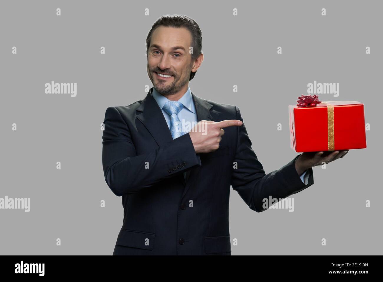 Smiling businessman pointing at gift box in his hand Stock Photo - Alamy