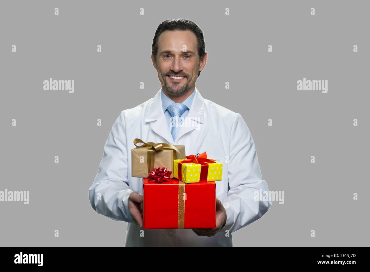 Happy male doctor holding many gift boxes Stock Photo - Alamy