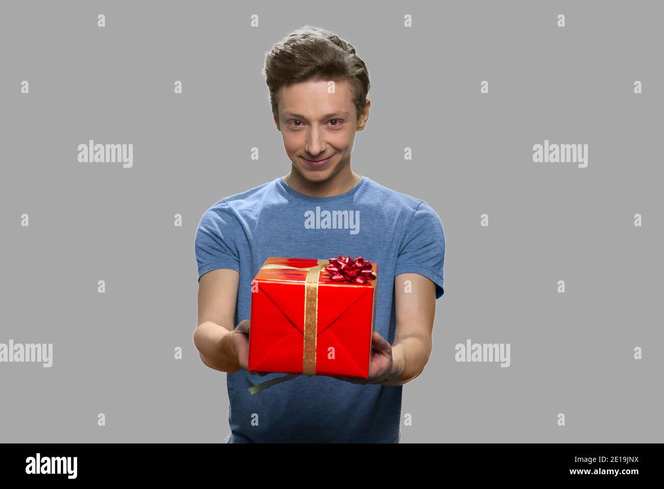 Handsome teen boy offering gift box to someone Stock Photo - Alamy