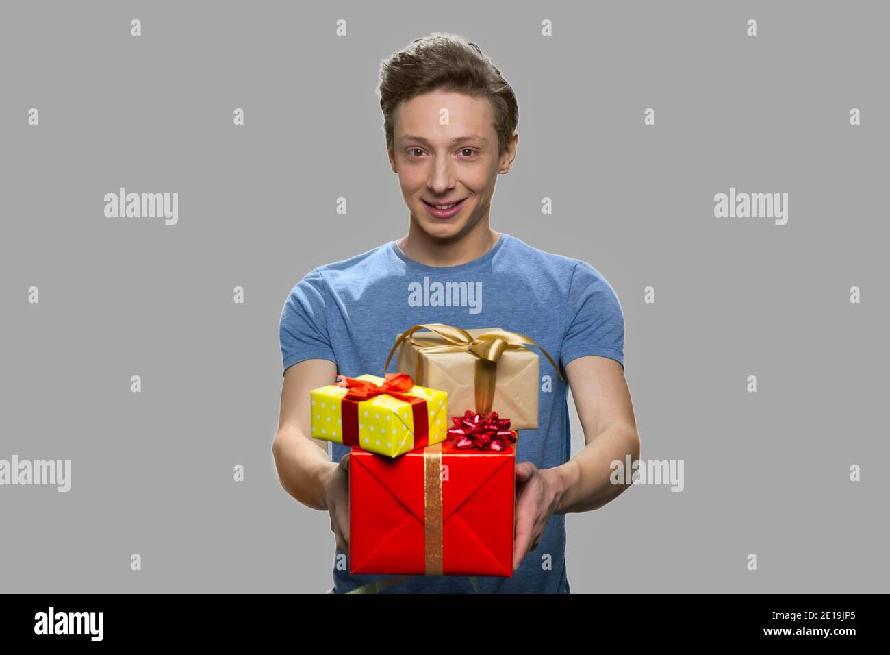 Portrait of teenage boy offering gift boxes Stock Photo - Alamy