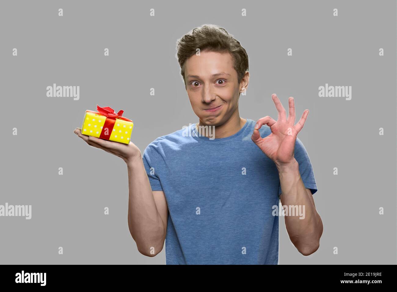 Teen boy with gift box showing ok symbol Stock Photo - Alamy