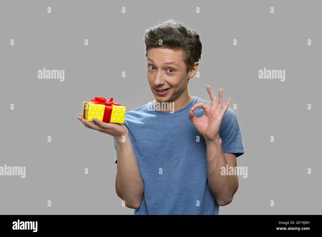 Teenage boy showing gift box and ok gesture Stock Photo - Alamy