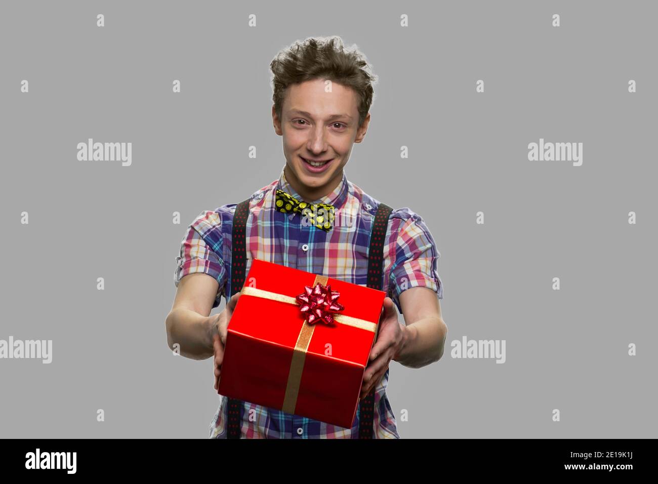 Smiling teenage boy offering gift box Stock Photo - Alamy
