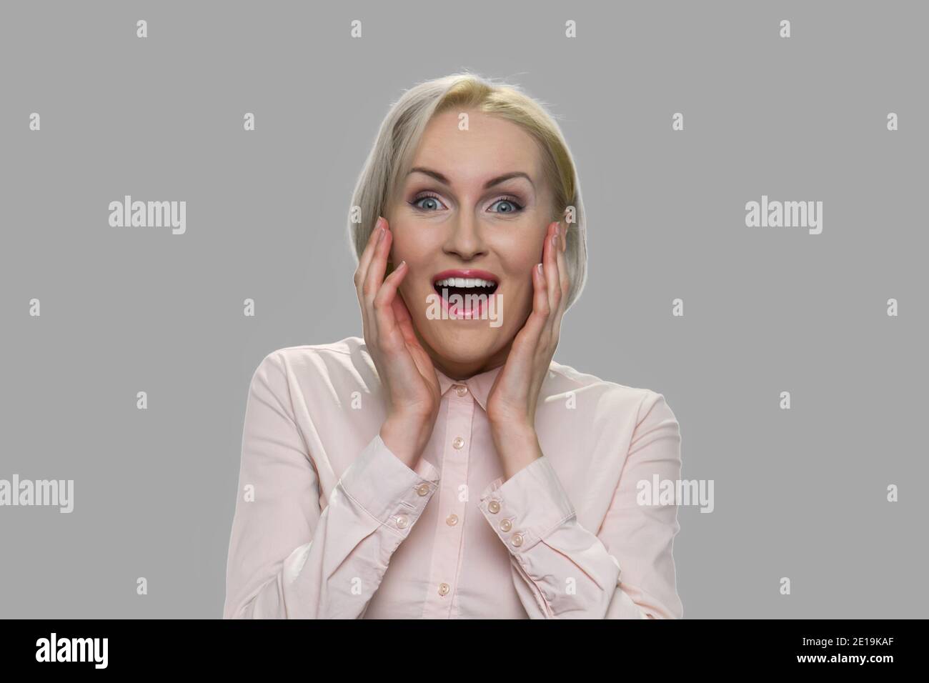 Portrait of shocked woman on gray background Stock Photo - Alamy