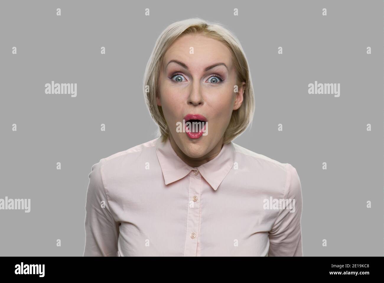 Happy stunned woman on gray background Stock Photo - Alamy