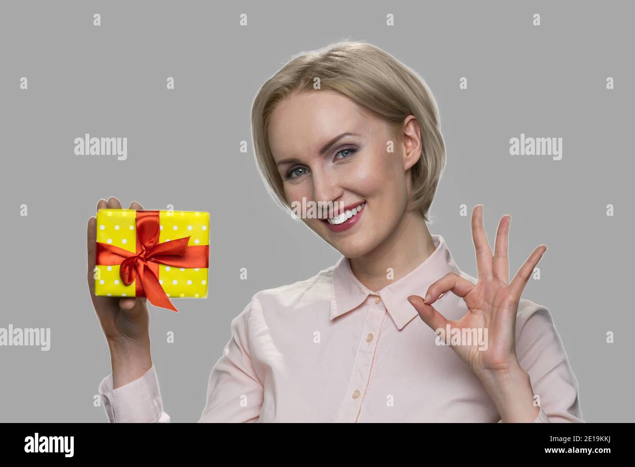 Woman showing gift box and OK sign Stock Photo - Alamy