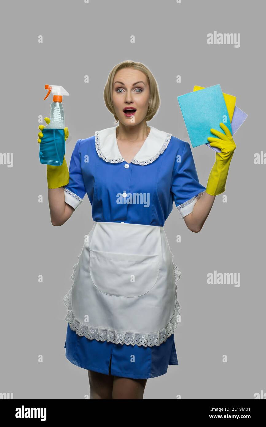 Happy shocked maid in uniform holding rags and detergent Stock Photo ...