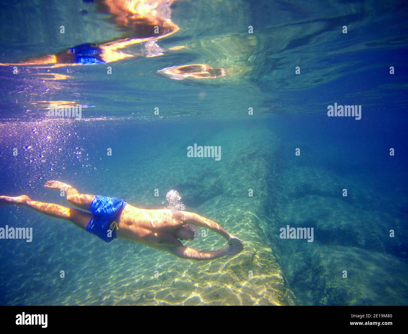Young handsome student man diving in the sea with a reflection of him ...