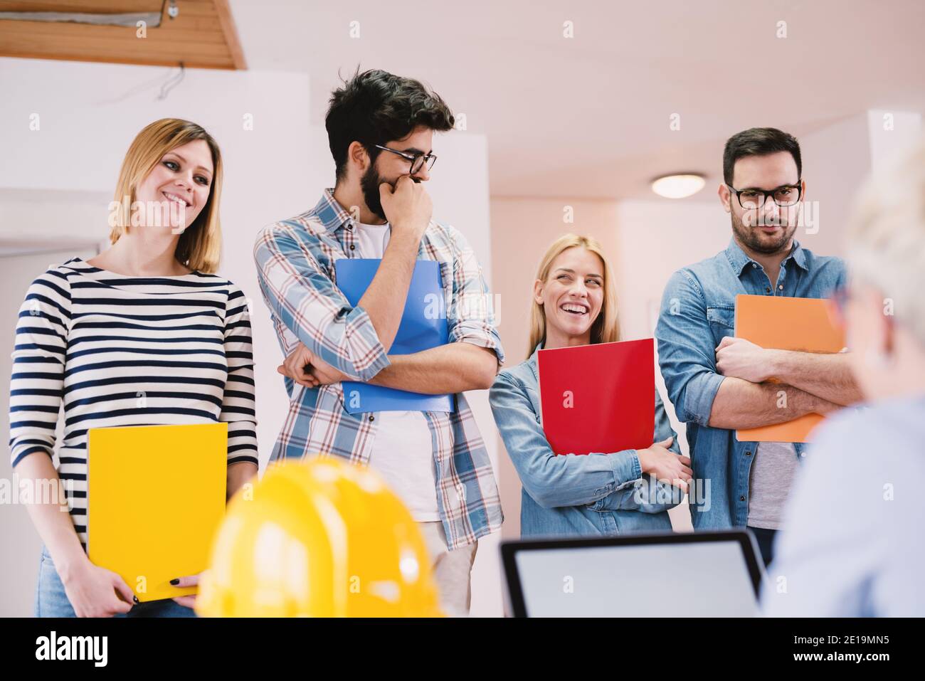 Group of young people having fun while waiting in the row with folders ...