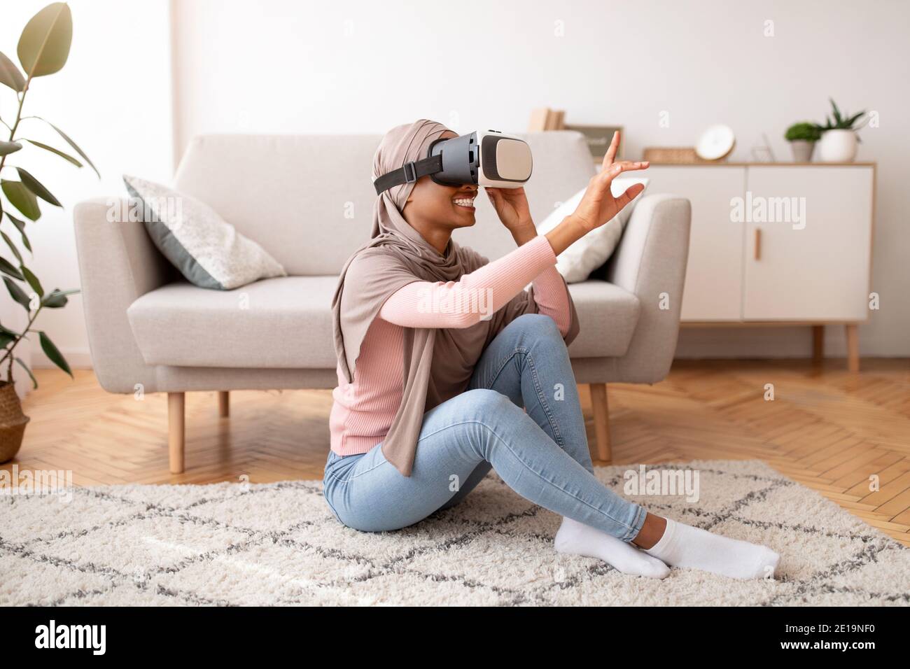 Happy Muslim woman in hijab and VR headset touching air, having virtual ...