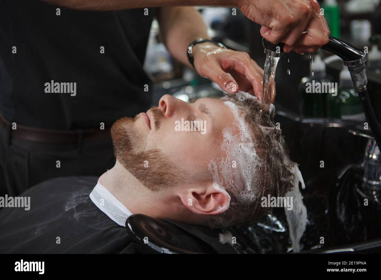 Close up of a barber washing hair of male client, using shampoo Stock ...