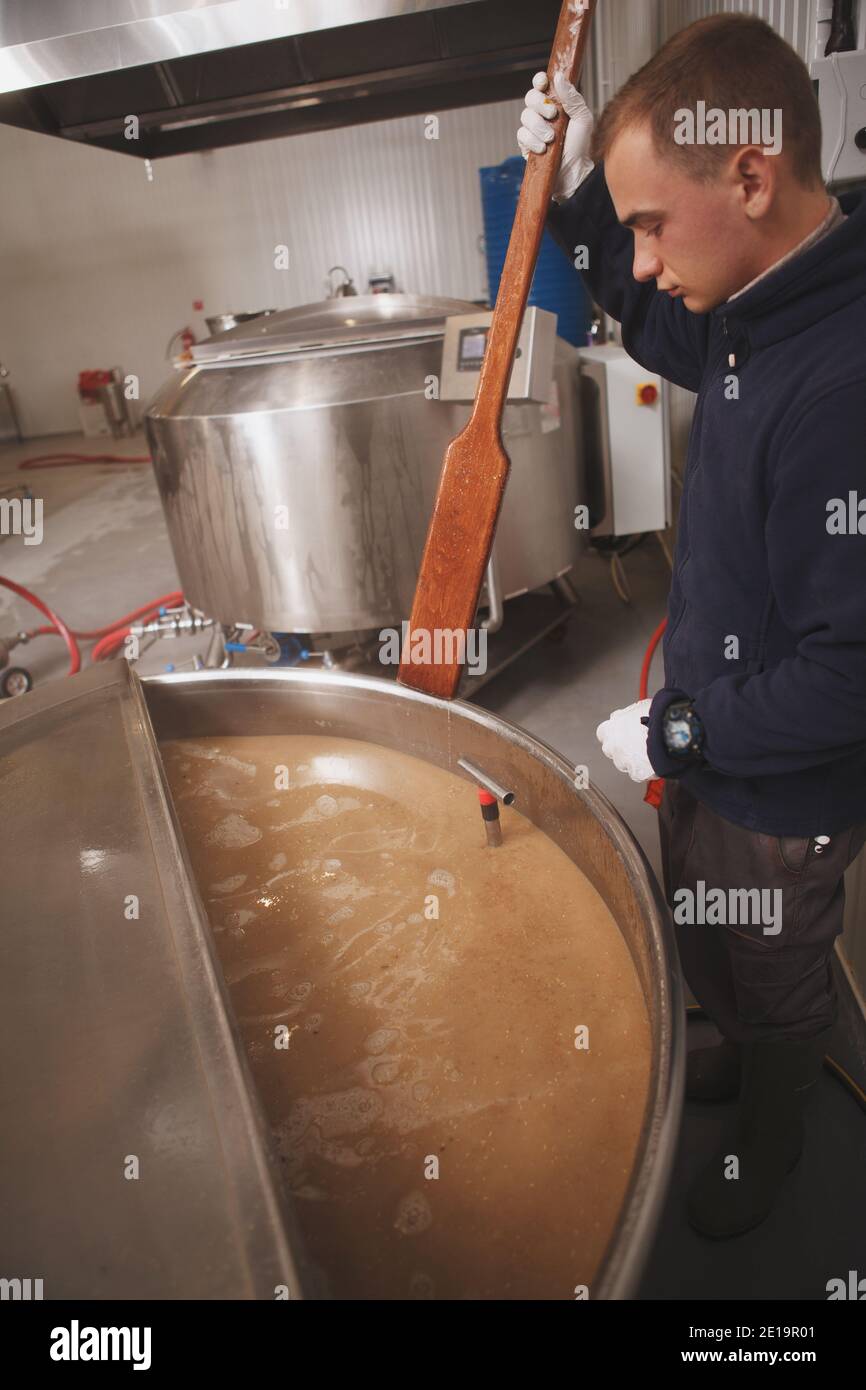 Professional brewer exmining beer in a tank during fermentation ...