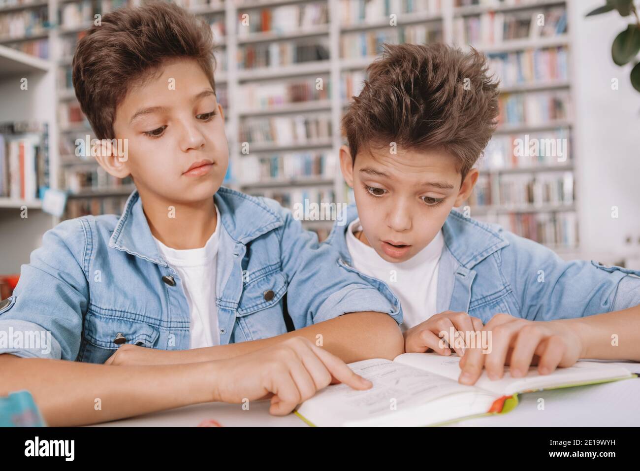 Young boy looking shocked when his brother showing him something a book ...