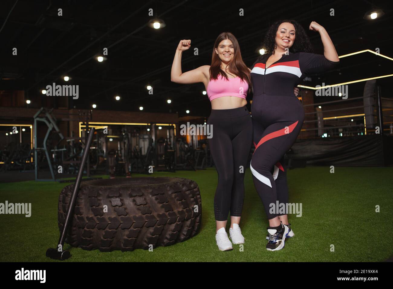 Two happy confident plus size women smiling, flexing their biceps at ...