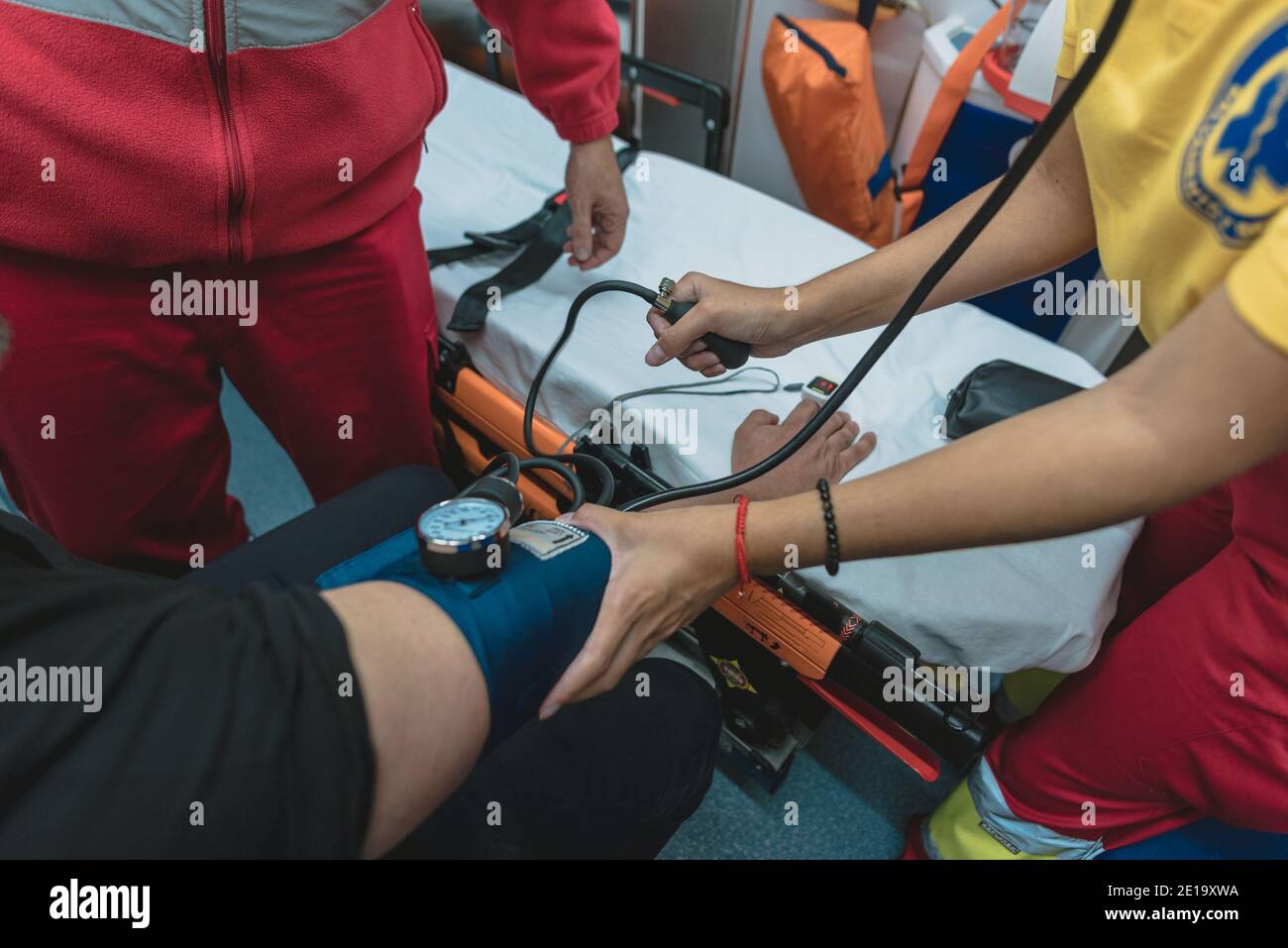 a group of health workers help a patient do tests inside an ambulance ...