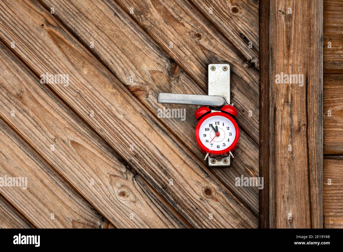 Red alarm clock hanging on the wooden door handle Stock Photo - Alamy