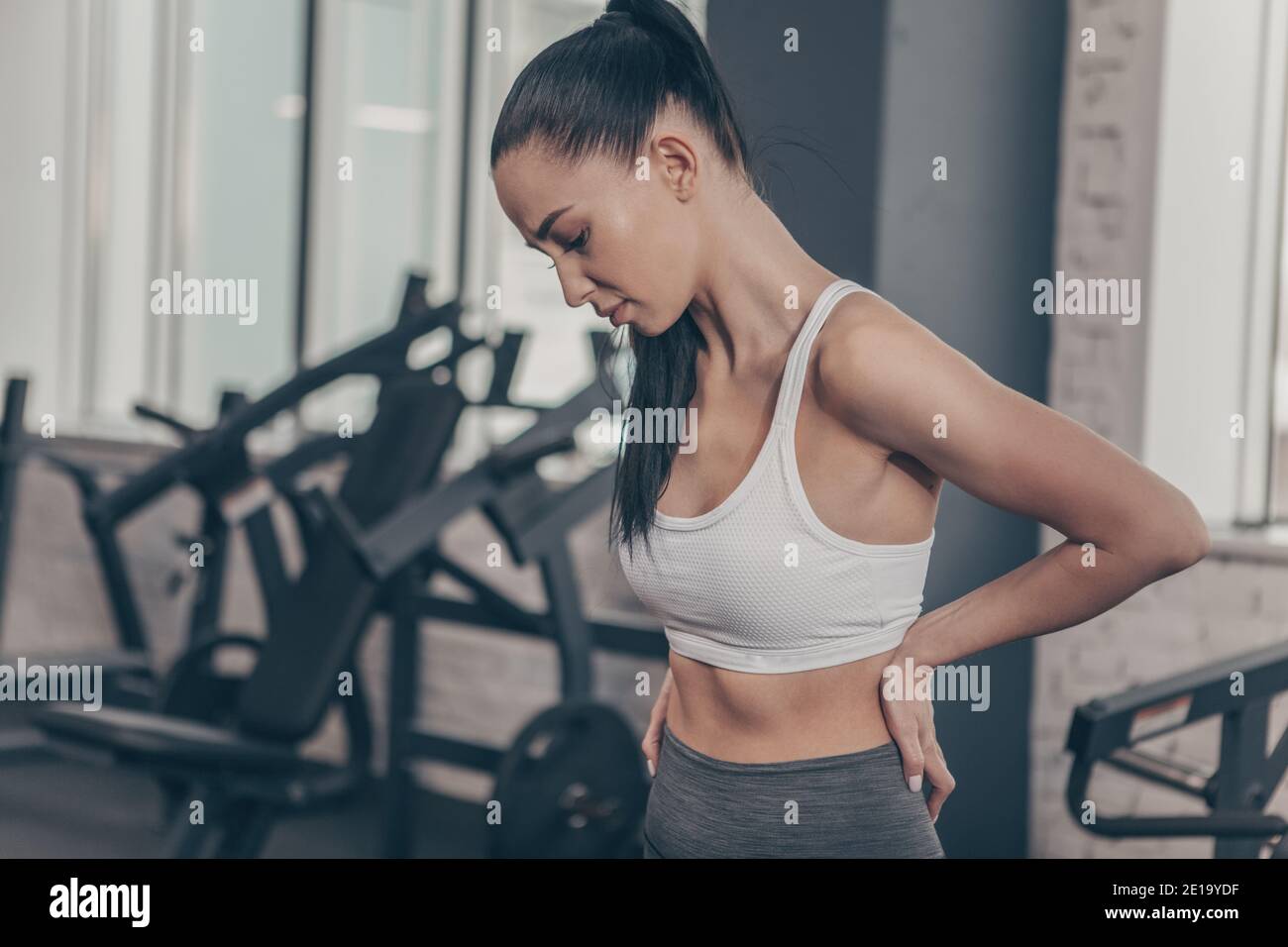 Beautiful athletic woman having backache after workout at the gym ...