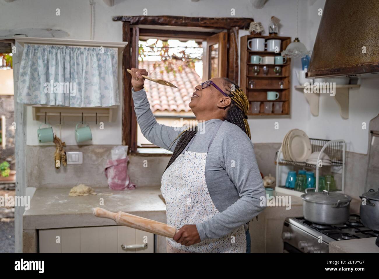 a black woman dances and sings happily and happily while cooking in a ...