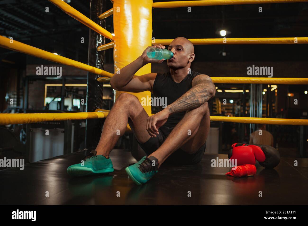 Full length shot of a young athletic African male boxer drinking water ...