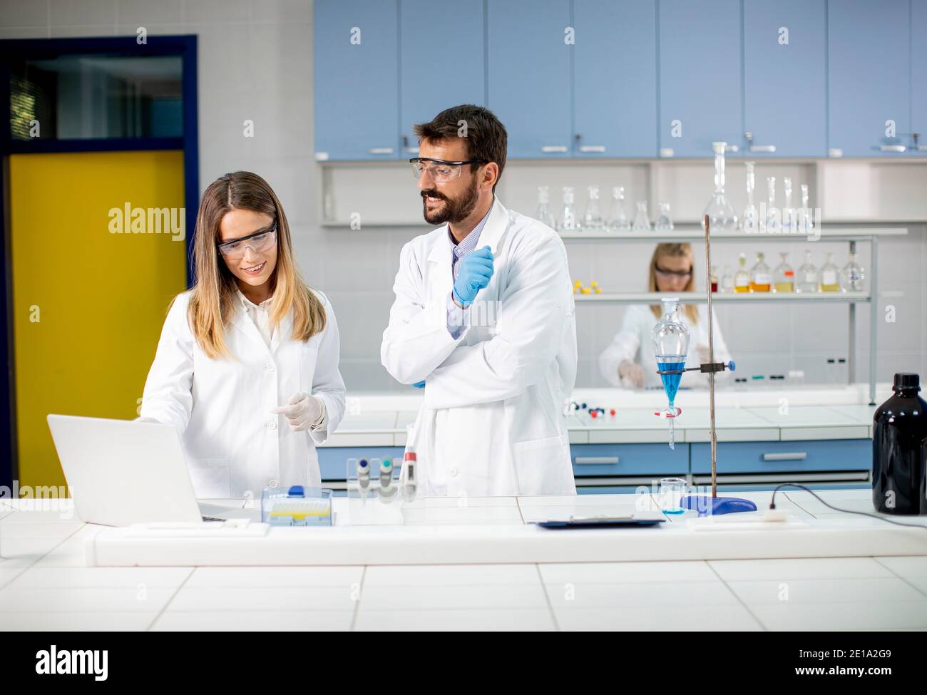 Researchers working with blue liquid at separatory funnel in the ...